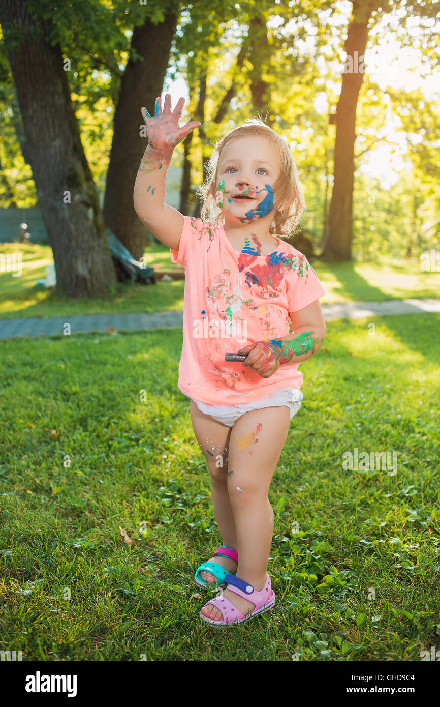 Two-year old girl stained in colors against green lawn Stock Photo - Alamy