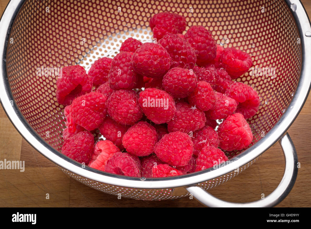 Fresh raspberries in stainless steel colander on a wood surface Stock ...