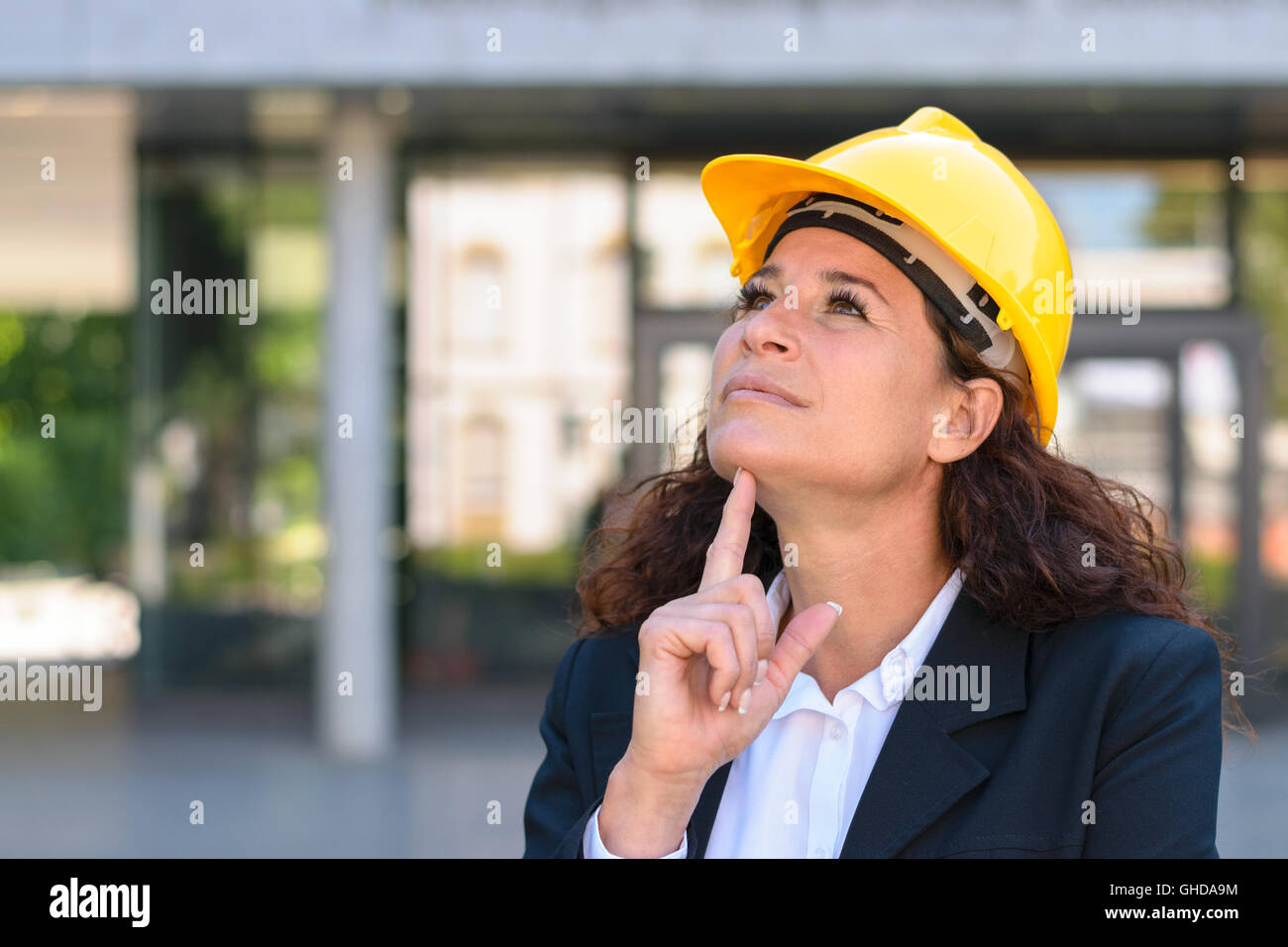 Thoughtful young female architect or building inspector standing ...