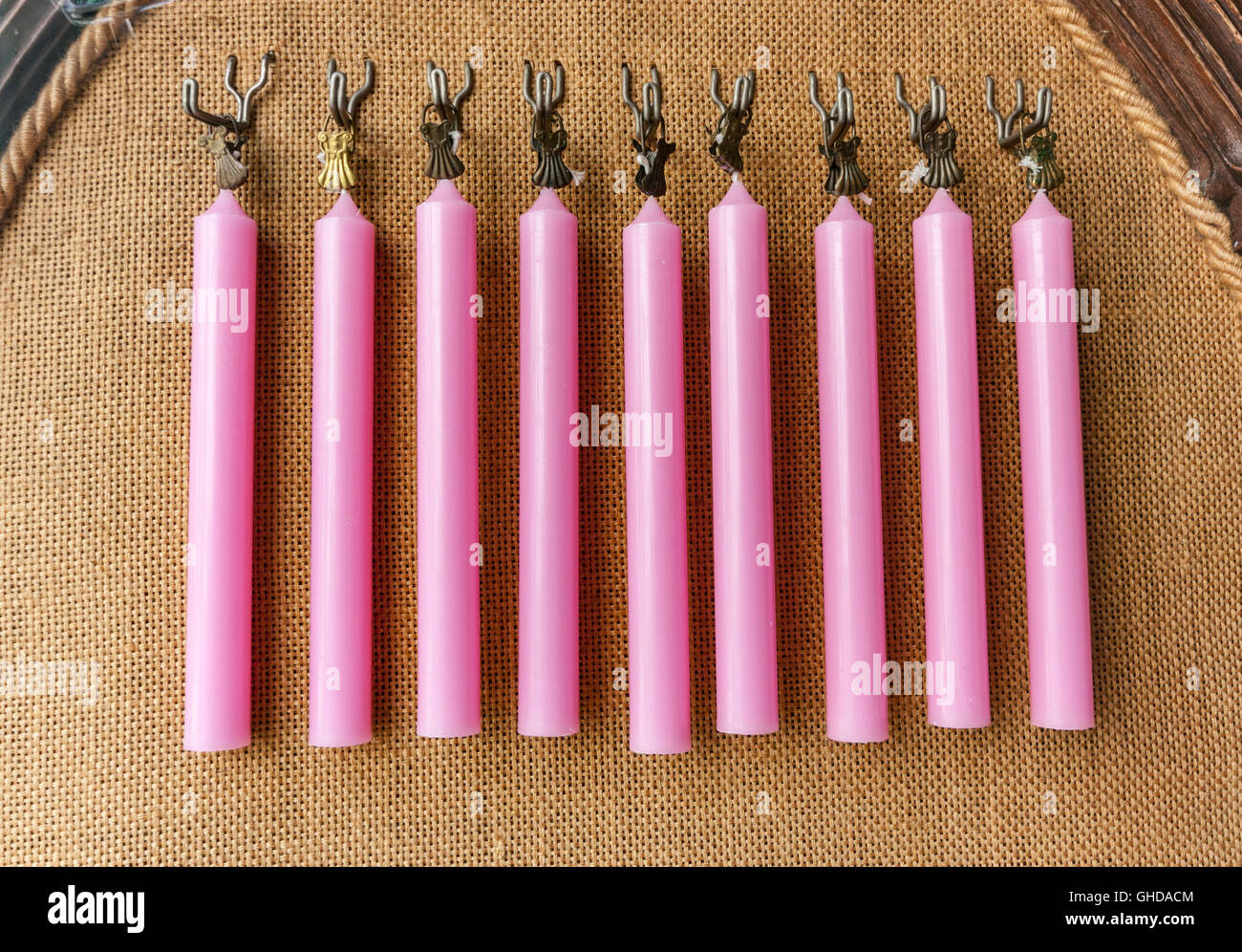 9 pink candles on a hessian background Stock Photo - Alamy