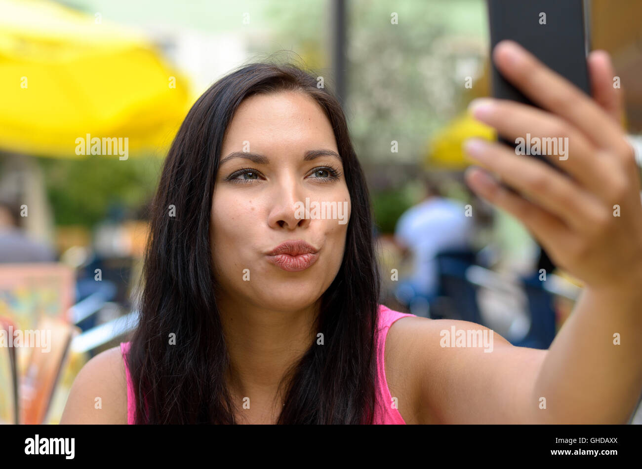 Woman puckering lips while taking picture of herself with cellular ...