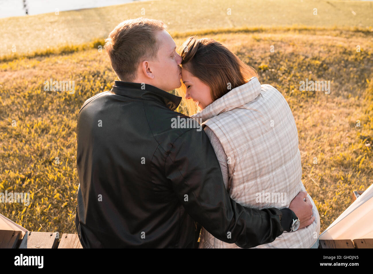 Romantic Young Couple Enjoying Autumn Nature Sitting In A Close Embrace View From Behind Stock