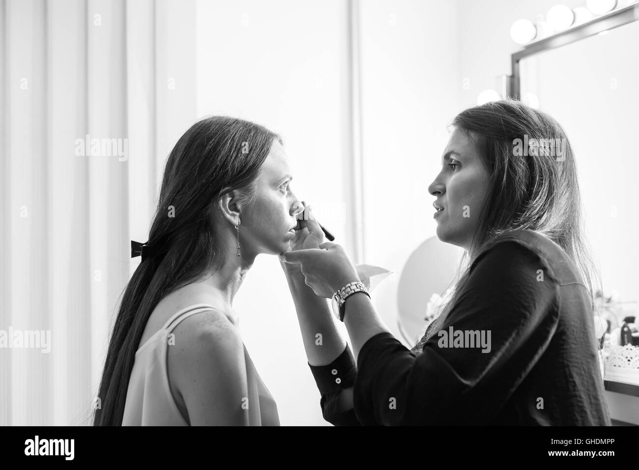 Woman applying makeup to model in salon Stock Photo - Alamy