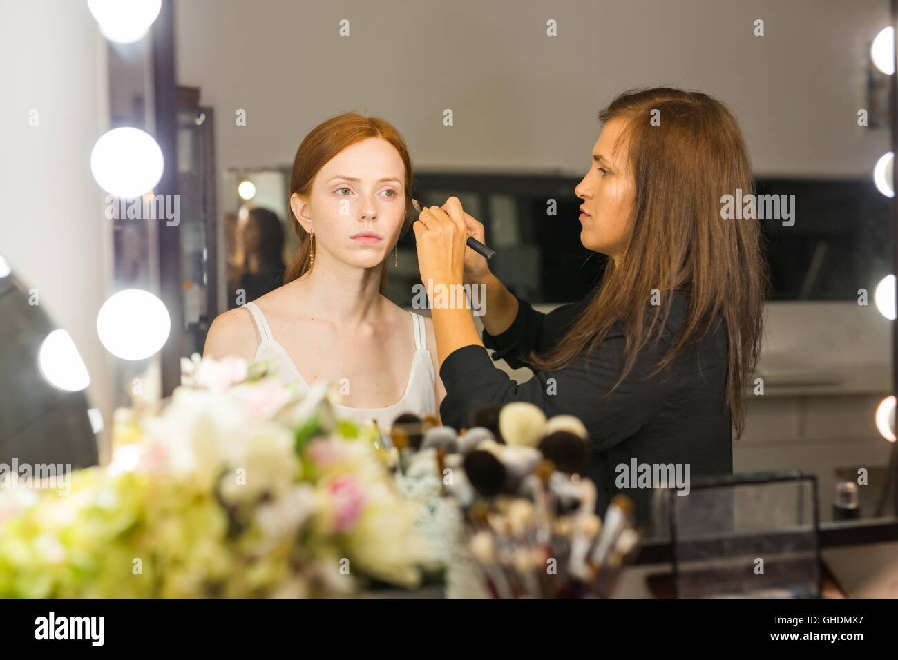 Woman applying makeup to model in salon Stock Photo - Alamy