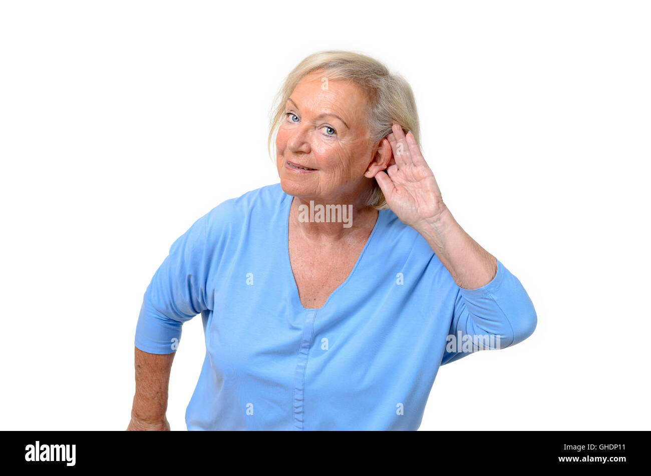 Hard of hearing attractive elderly woman holding her hand behind her ...