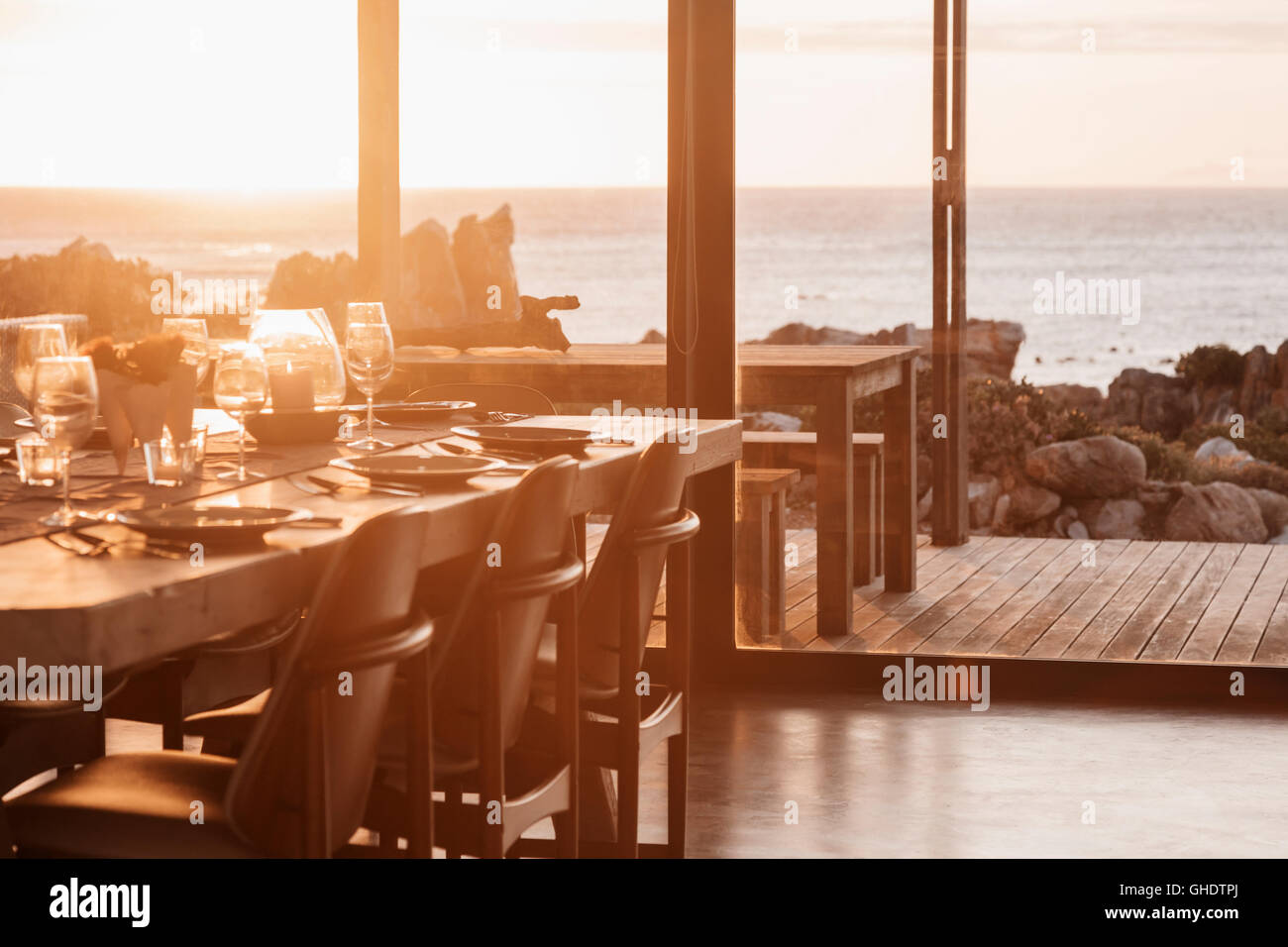 Sunny home showcase dining room overlooking ocean at sunset Stock Photo ...