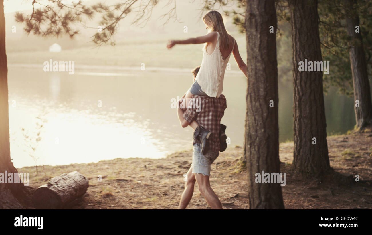 Young man carrying woman on shoulders at lakeside Stock Photo - Alamy