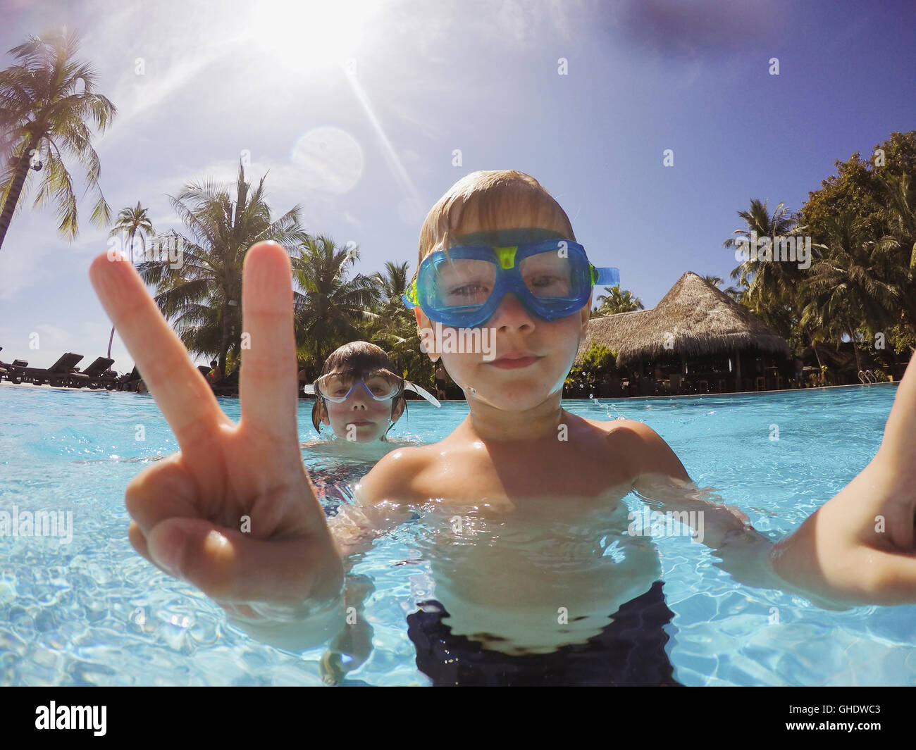 Portrait of boy gesturing peace sign in tropical swimming pool Stock ...