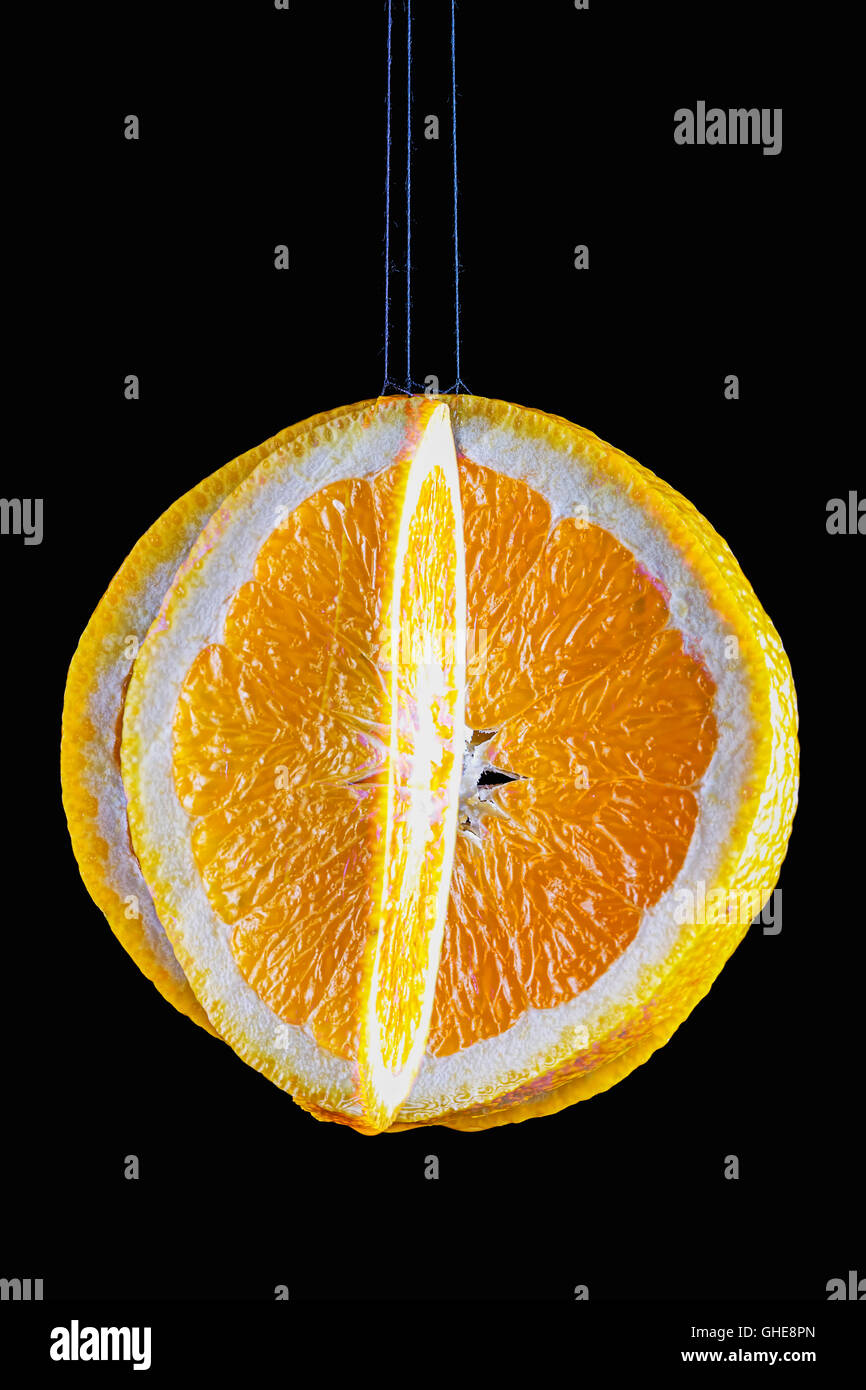 Spinning orange slice backlit on black background Stock Photo - Alamy