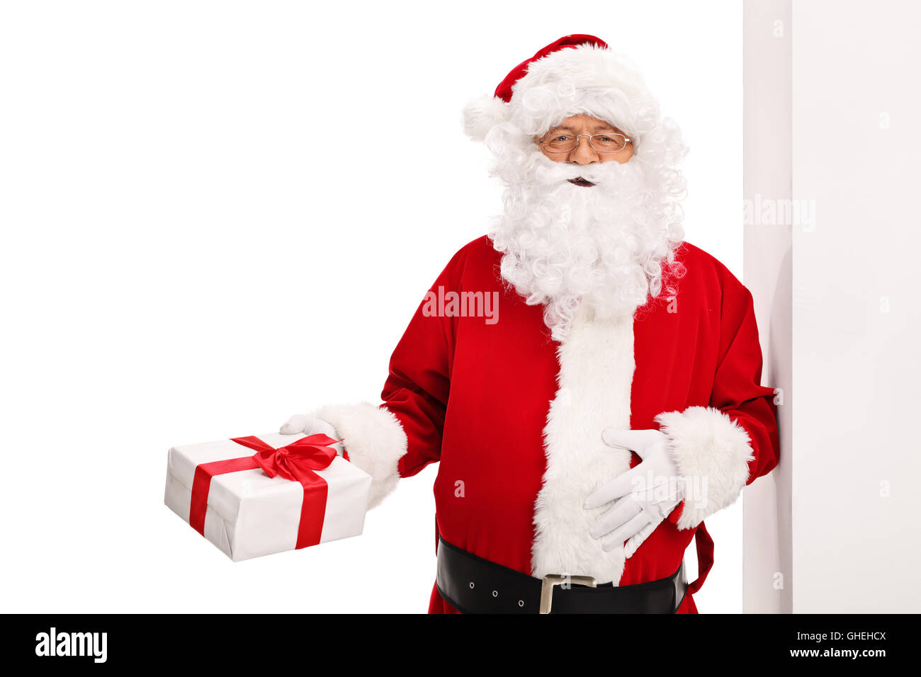 Santa Claus leaning against a wall and holding a present isolated on ...