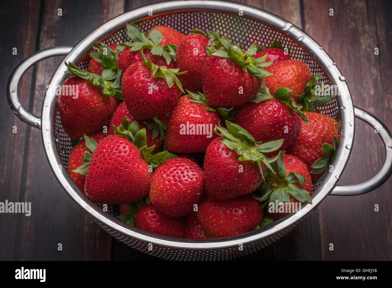 Fresh strawberries in stainless steel colander on a wood surface Stock ...