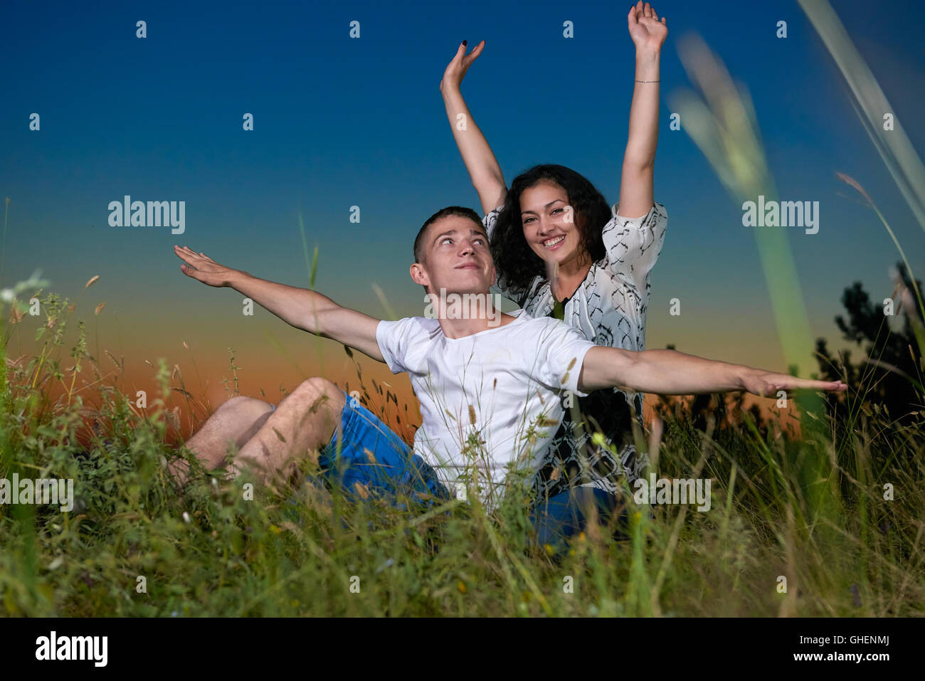 young romantic couple open arms and having fun at sunset on outdoor ...