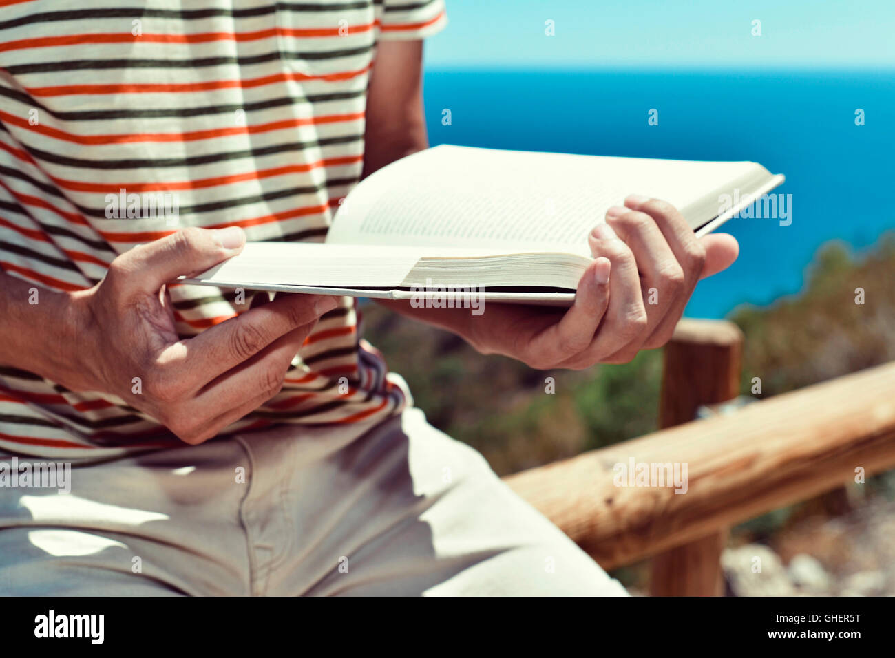 closeup of a young caucasian man reading a book outdoors, with the ...