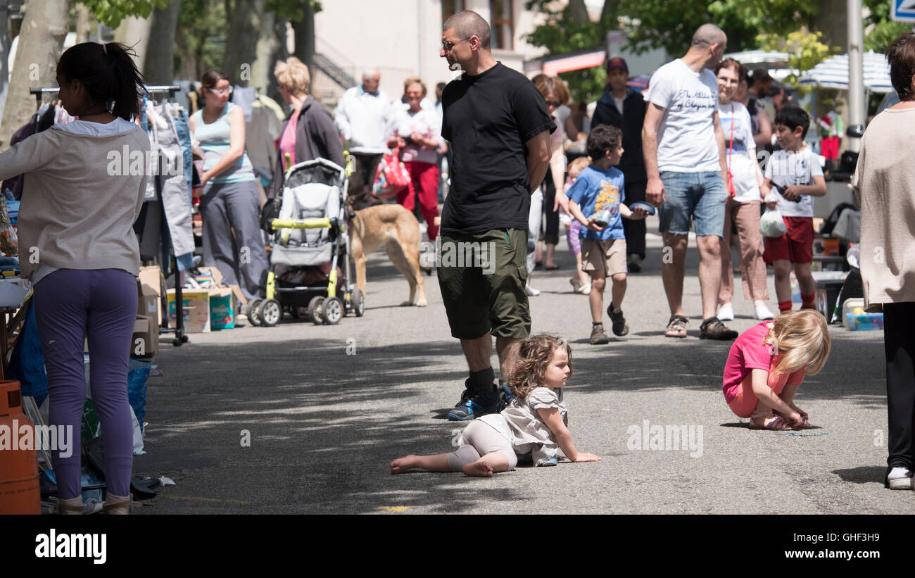 Children play happily on the street while parents shop at street market ...