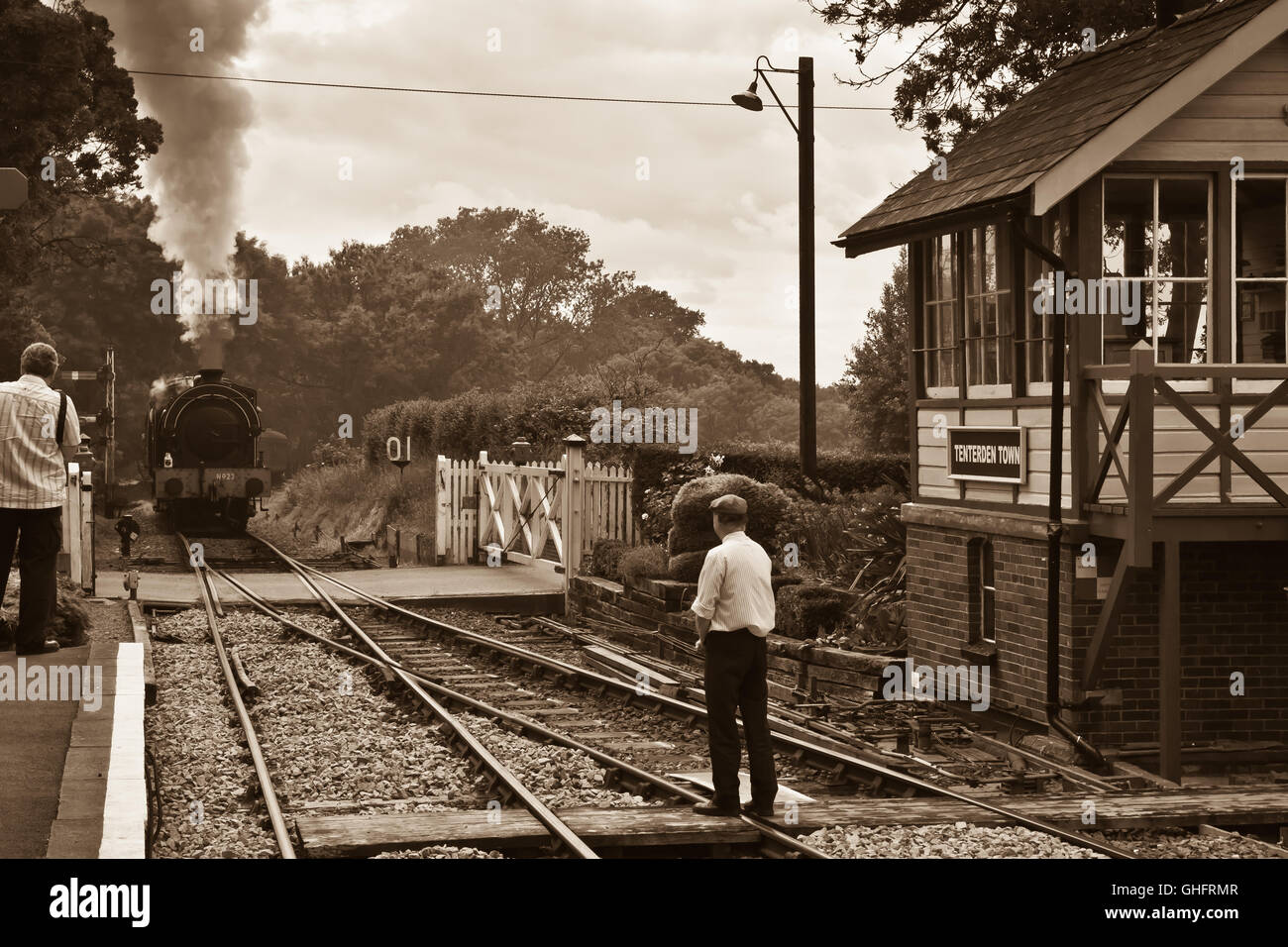 Sepia toned image of signalman on tracks as steam train approaches ...