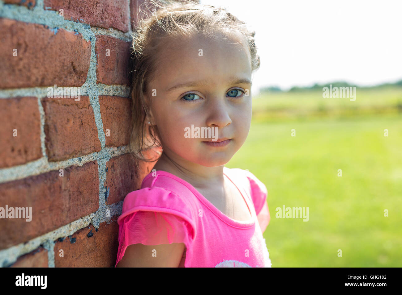Worried little girl brick house Stock Photo - Alamy