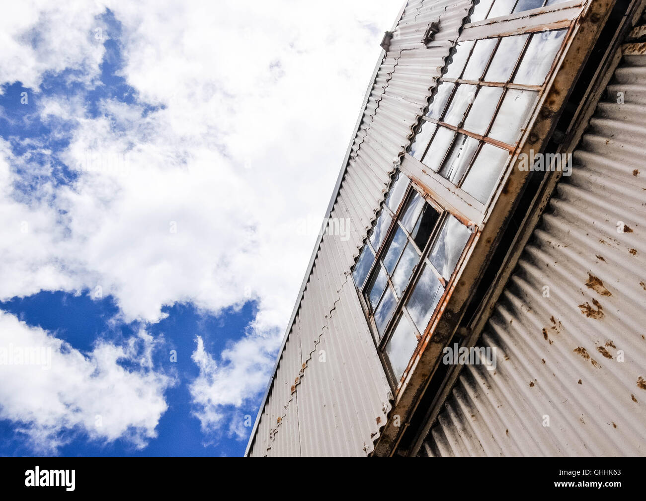 Upward perspective of old rusted metal pole building with windows under ...