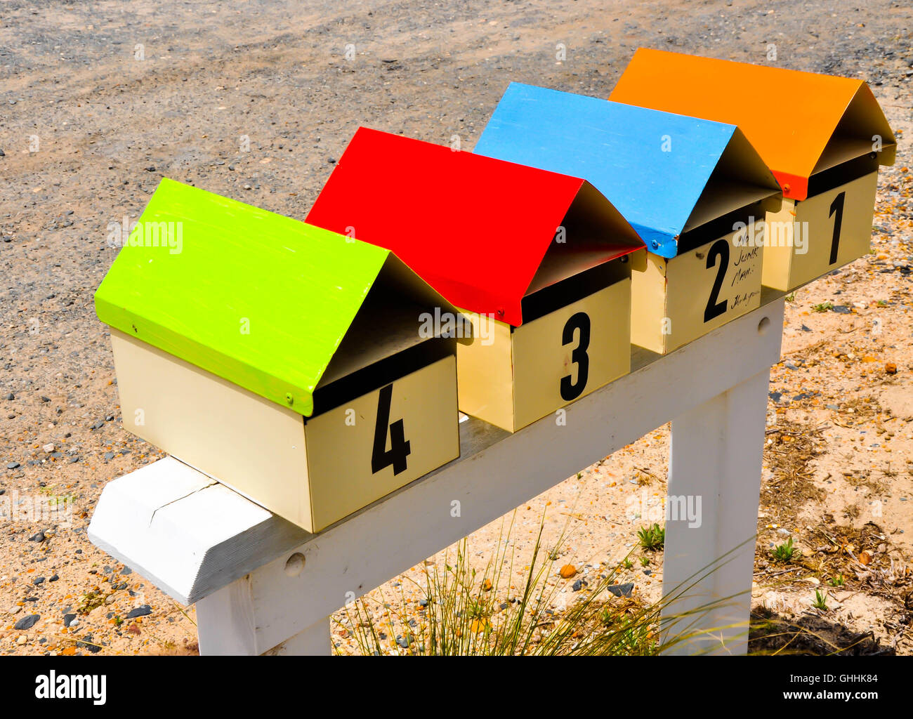 Row of four mailboxes, or letterboxes, with colorful lime green, red ...