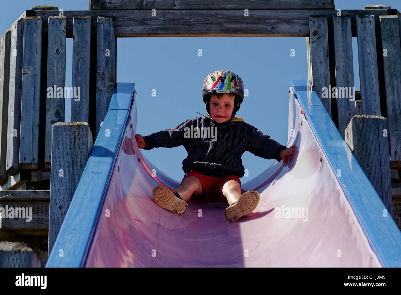 A scared boy (4 yrs old) sat looking down a long slide Stock Photo - Alamy
