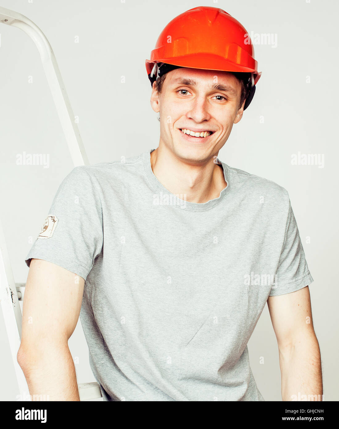 young real hard worker man isolated on white background on ladder ...