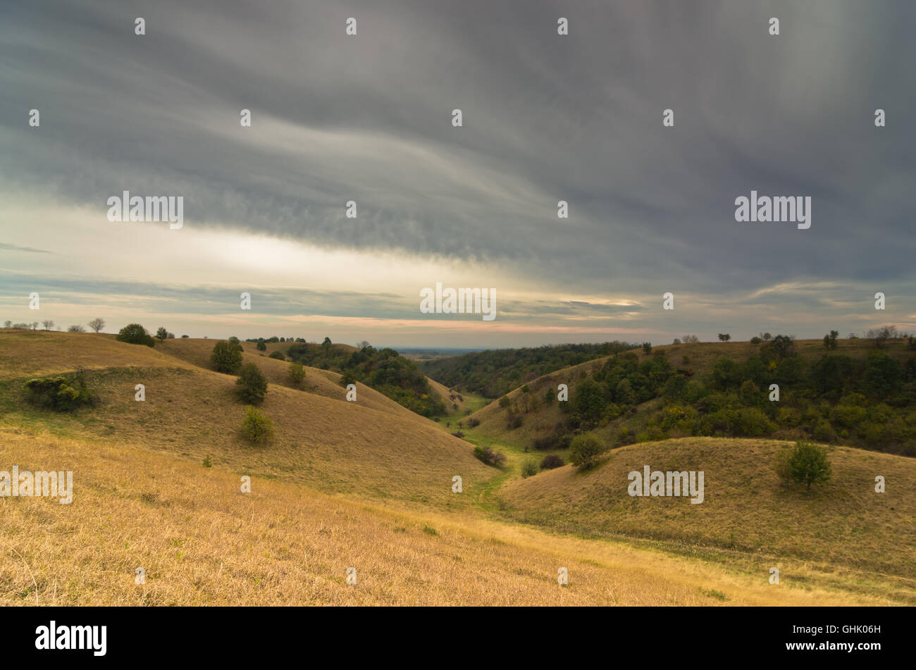Valley between small hills under dark clouds Stock Photo - Alamy