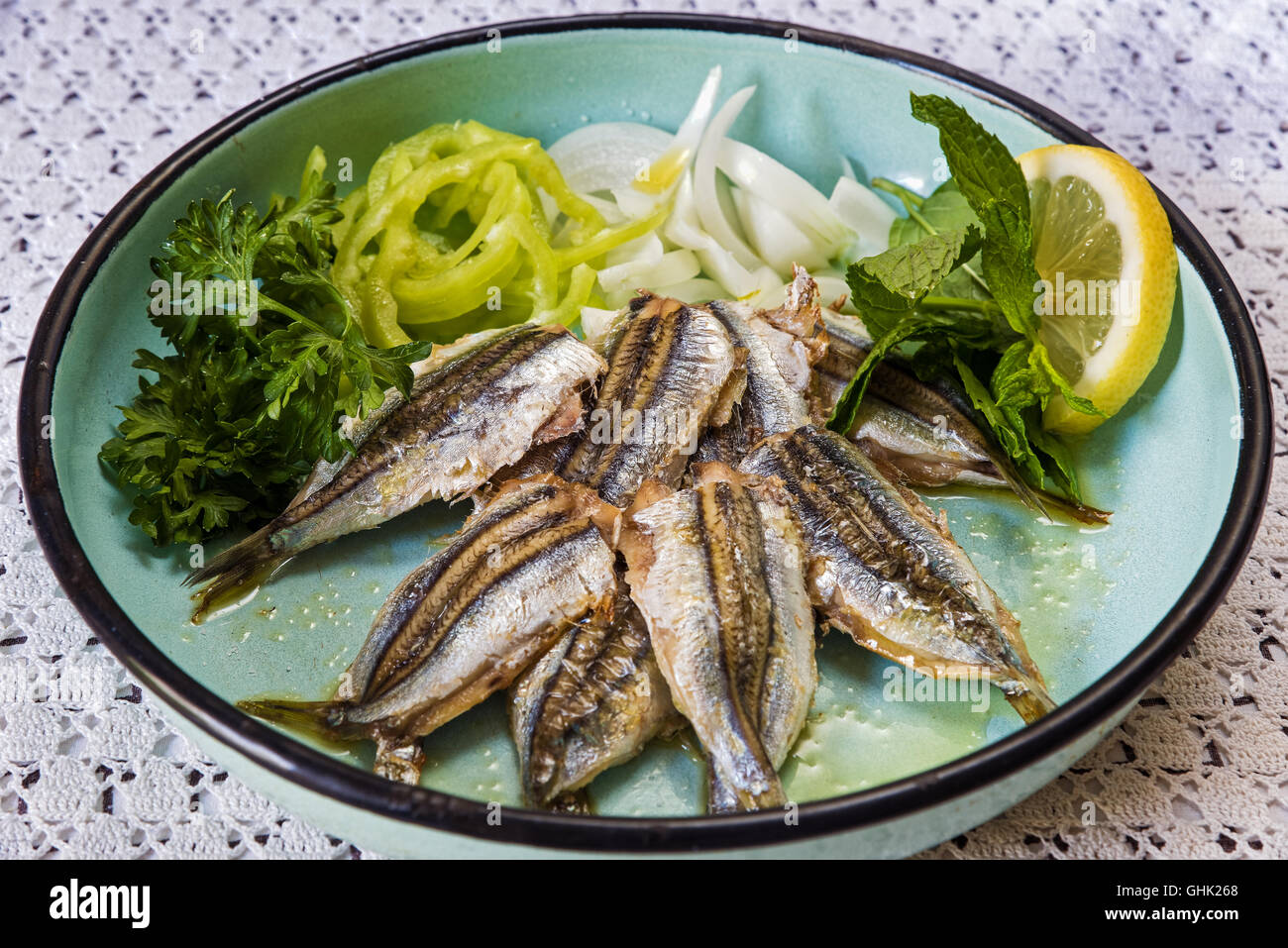 Cooked sardines with green salad in old-fashion plate on table Stock ...