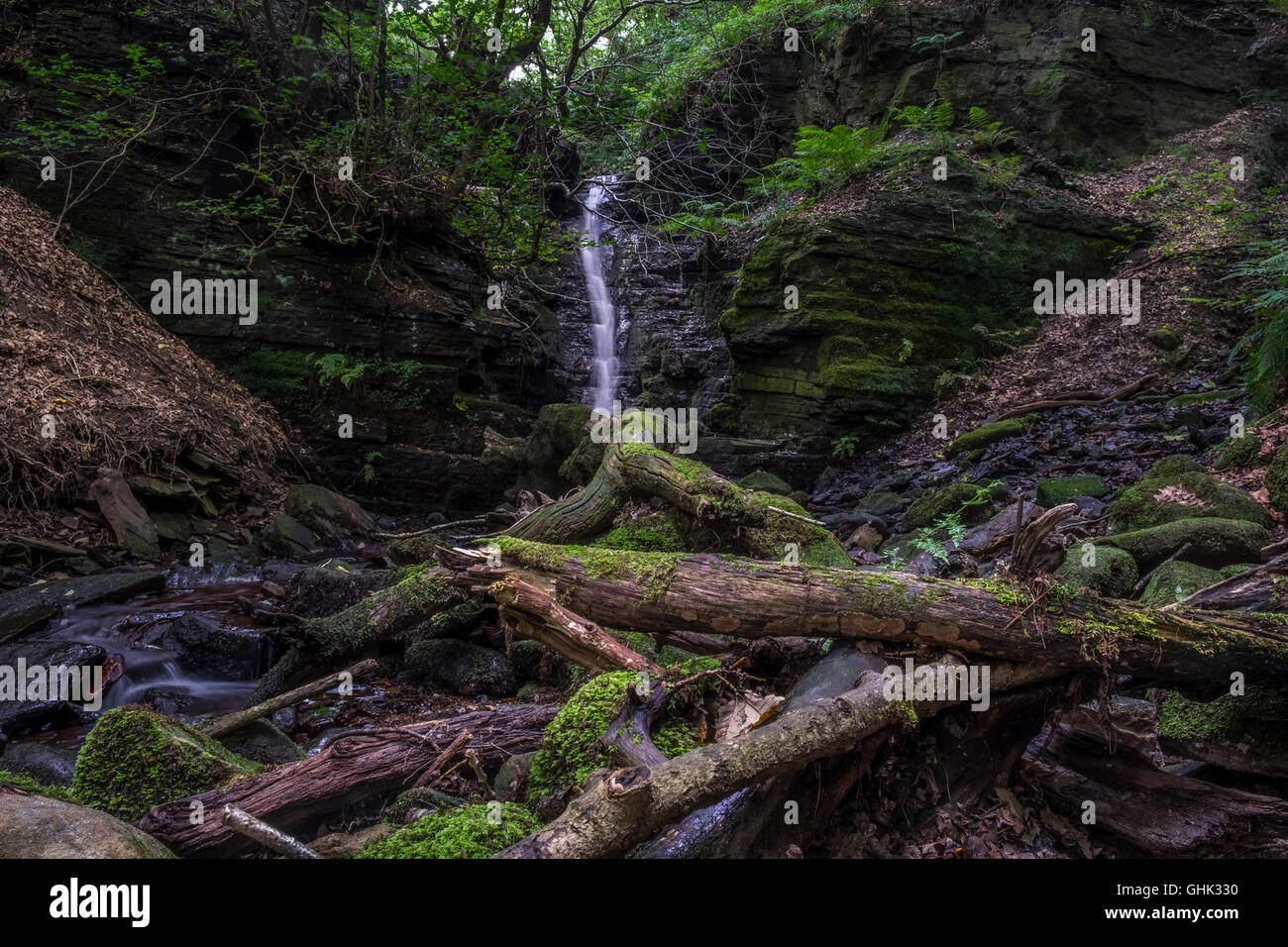 A small waterfall running down a small rock face into a small river ...