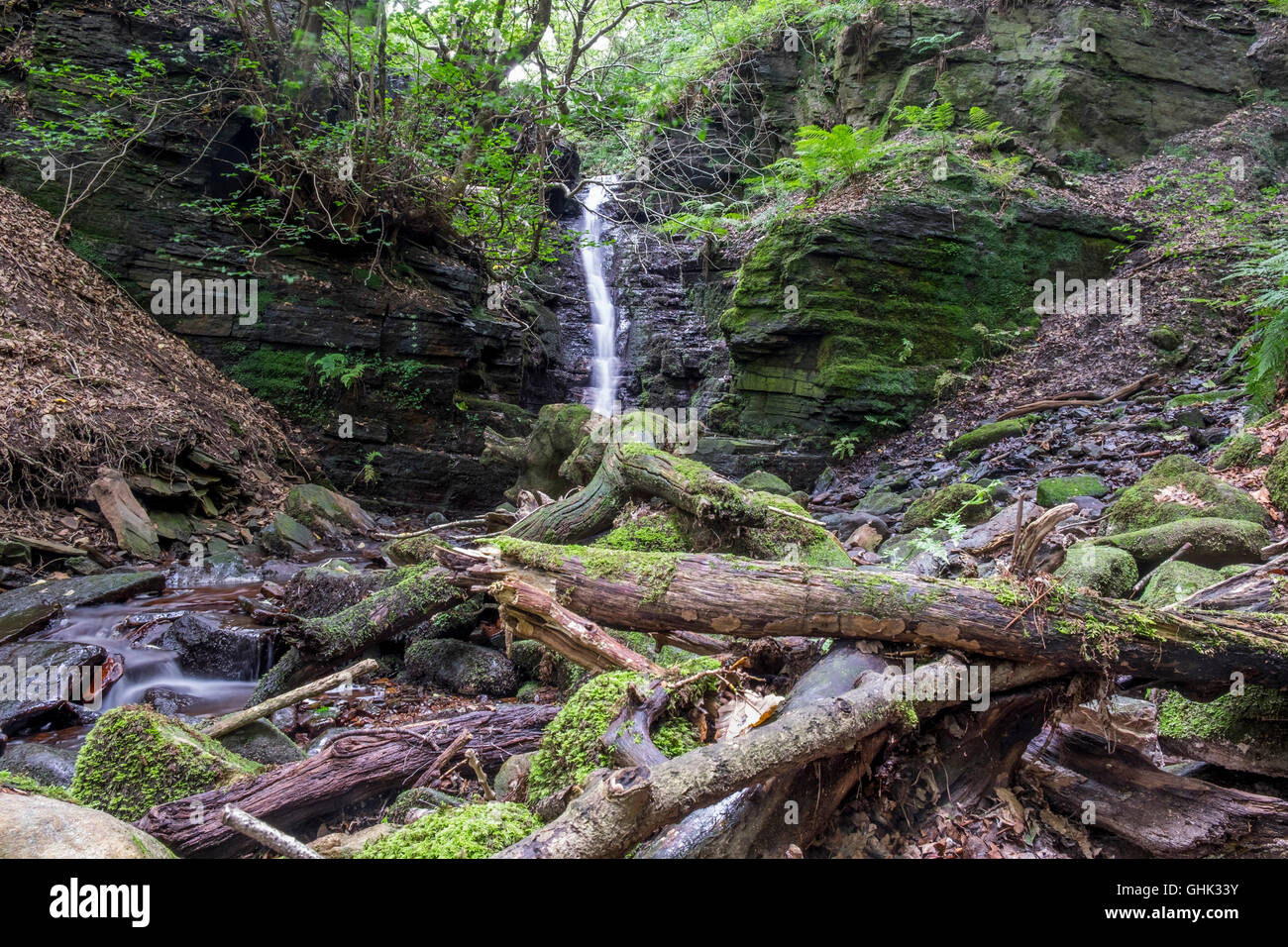 A small waterfall running down a small rock face into a small river ...