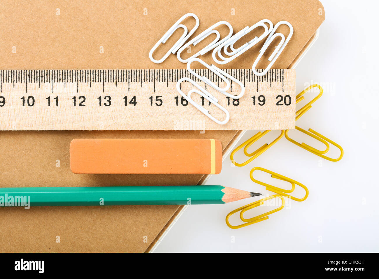 notebook, eraser, ruler, pencil and paperclips on white background ...