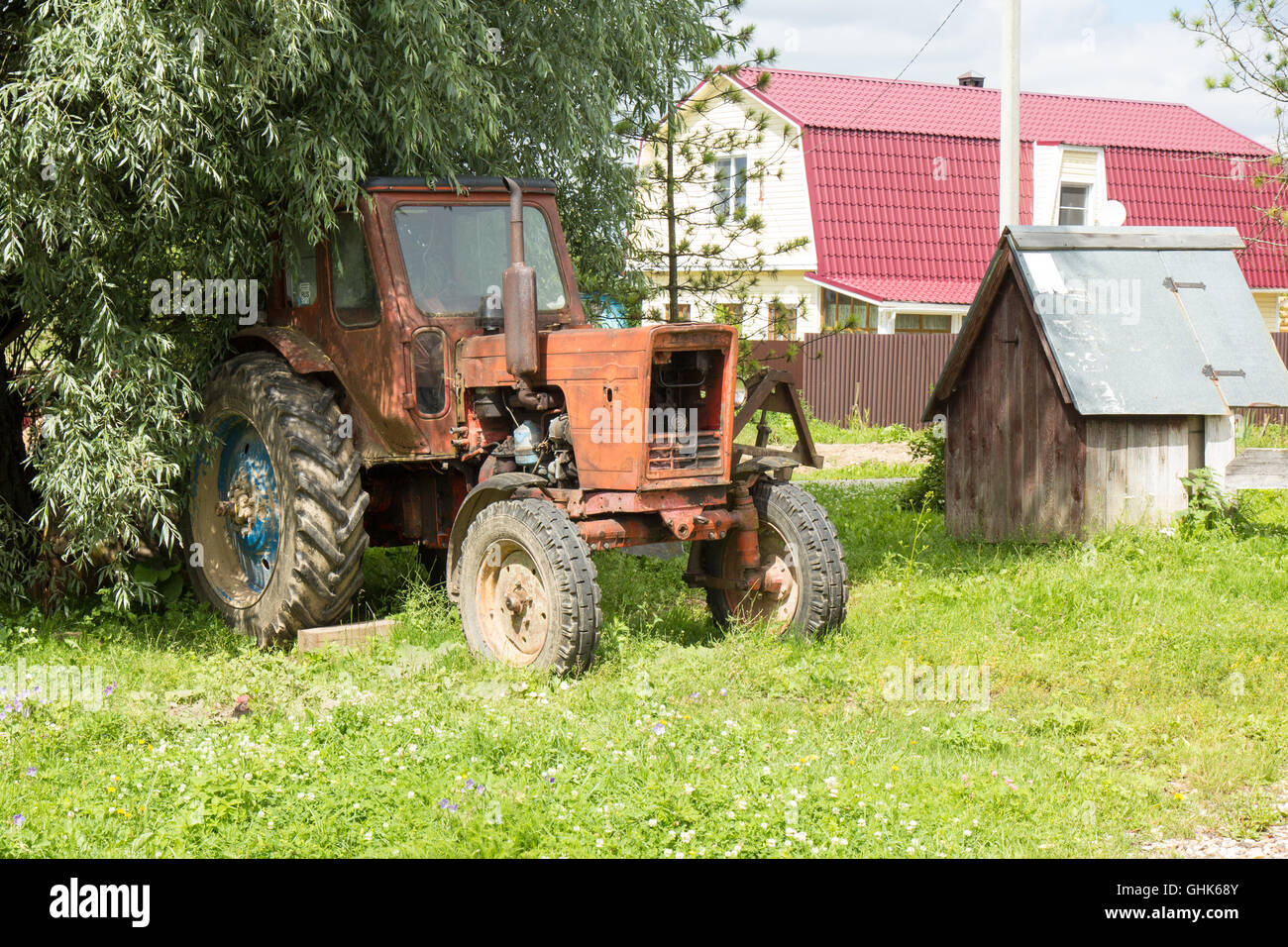 Old red rusty tractor near well on countryside Stock Photo - Alamy