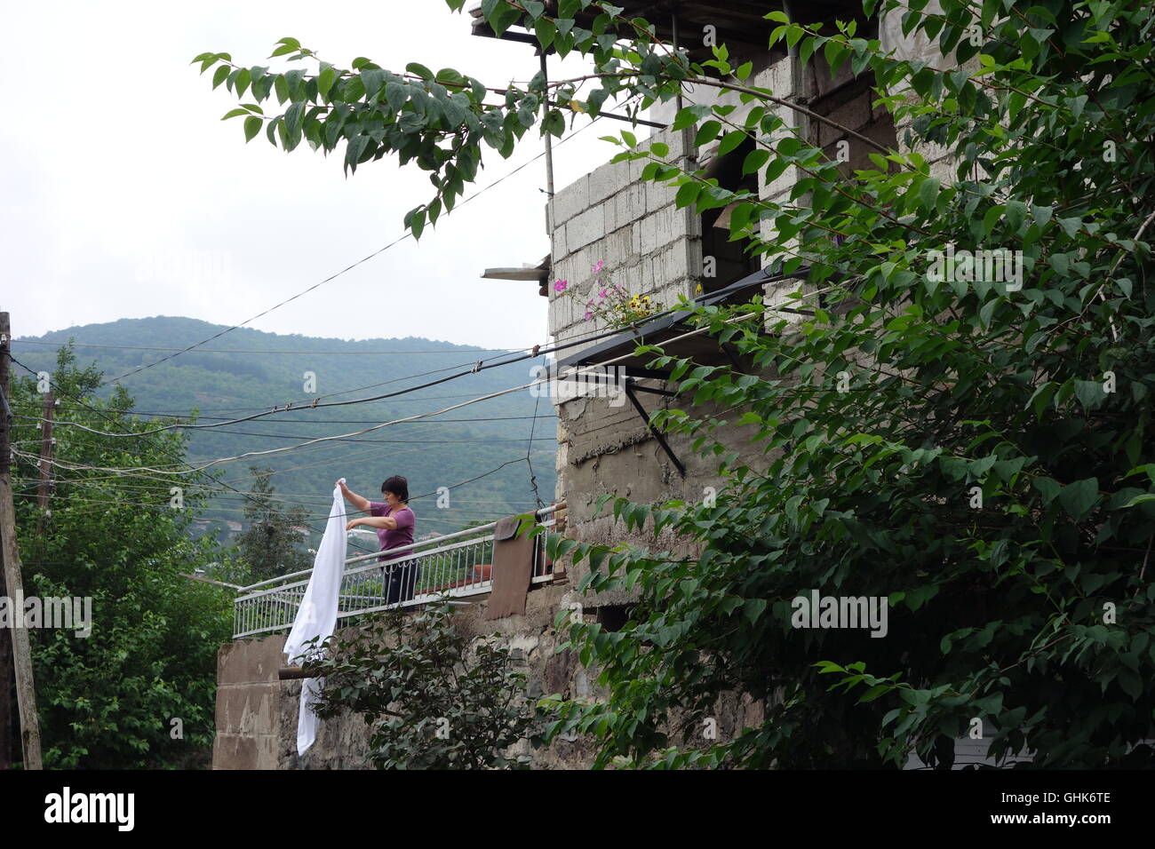 Goris Armenia town in mountains woman hanging out linen on balcony of ...