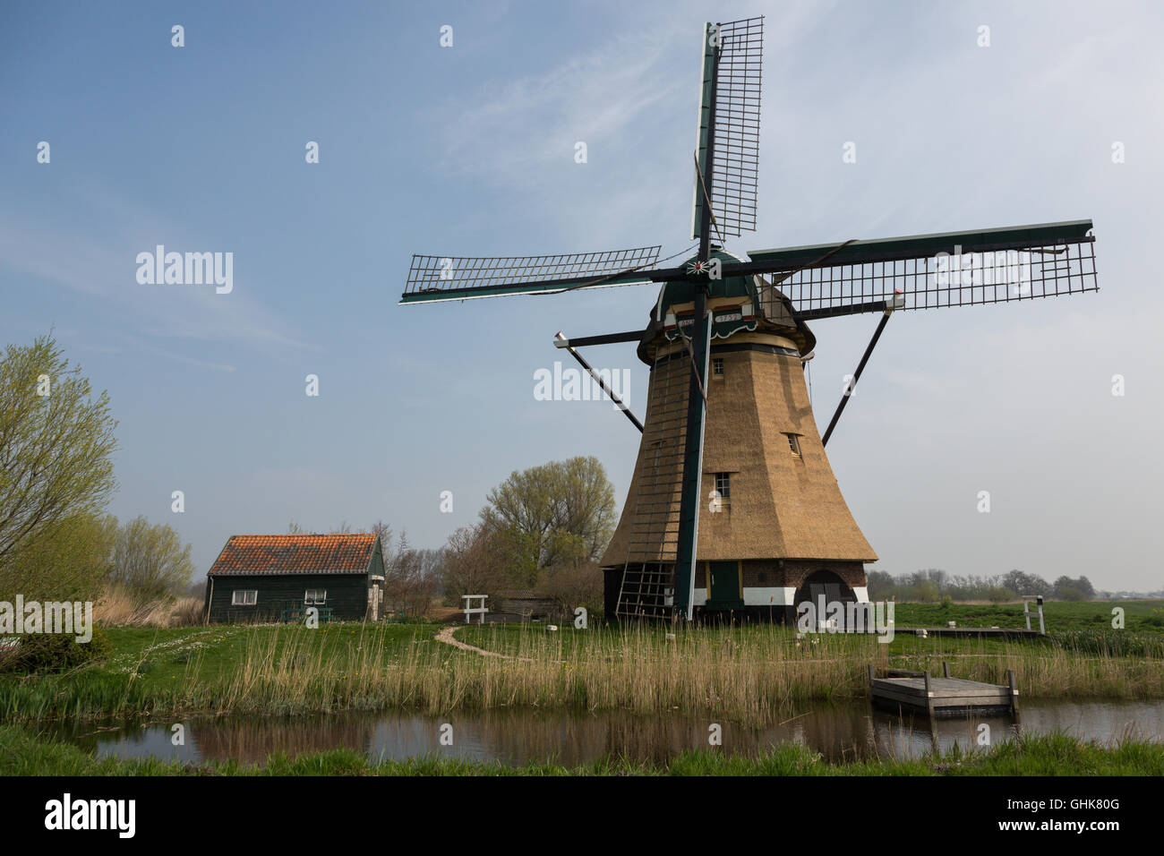 Dutch windmill with a bridge over water and a path in a dutch landscape ...