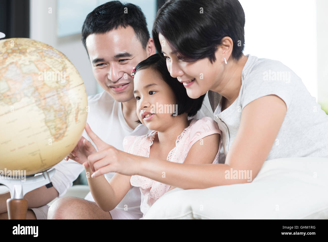 Young Asian parents exploring the globe with their child Stock Photo ...