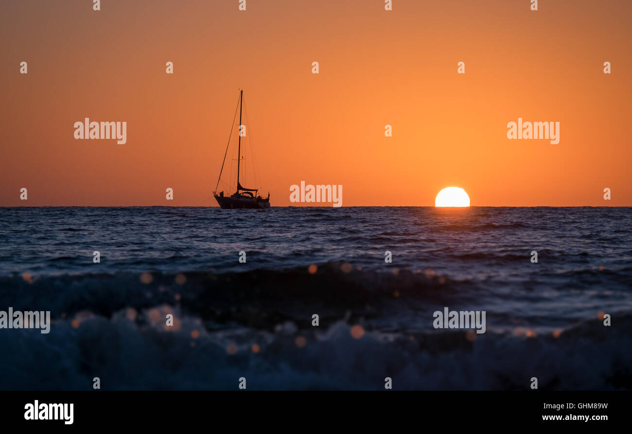 Sailboat on the ocean at sunset Stock Photo - Alamy
