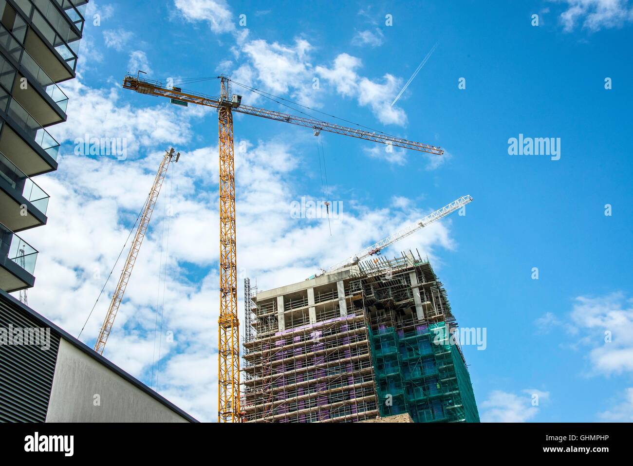 Cranes on building site of new apartment block with sky and jet stream ...