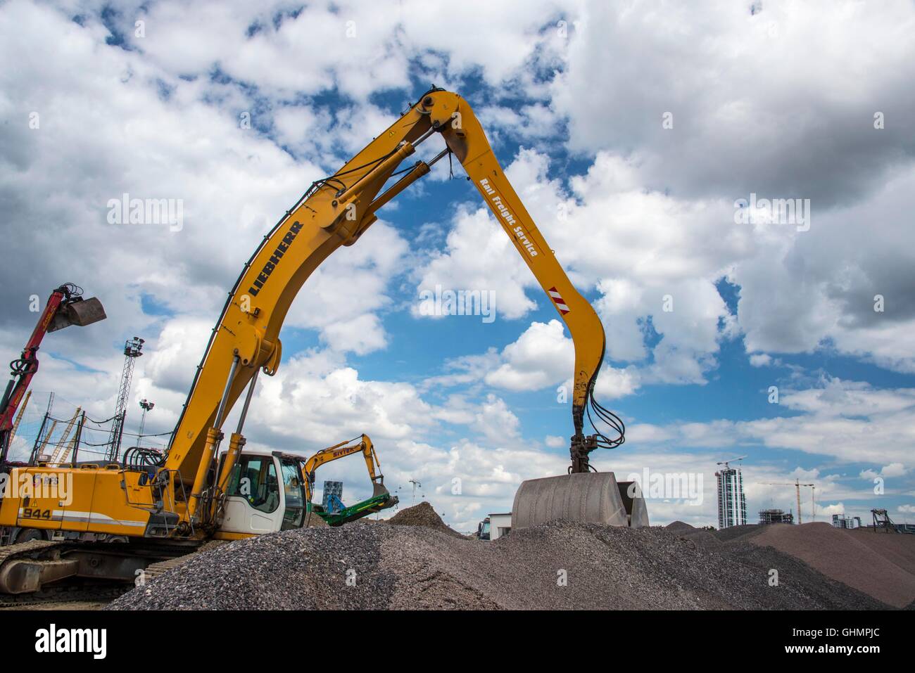 Digger moving gravel aggregates in gravel storage and sizing plant ...