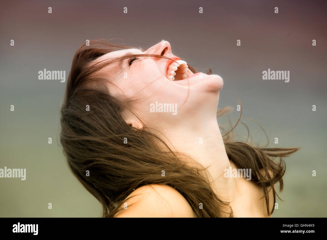 portrait of happy young brunette woman laughing with her eyes closed ...
