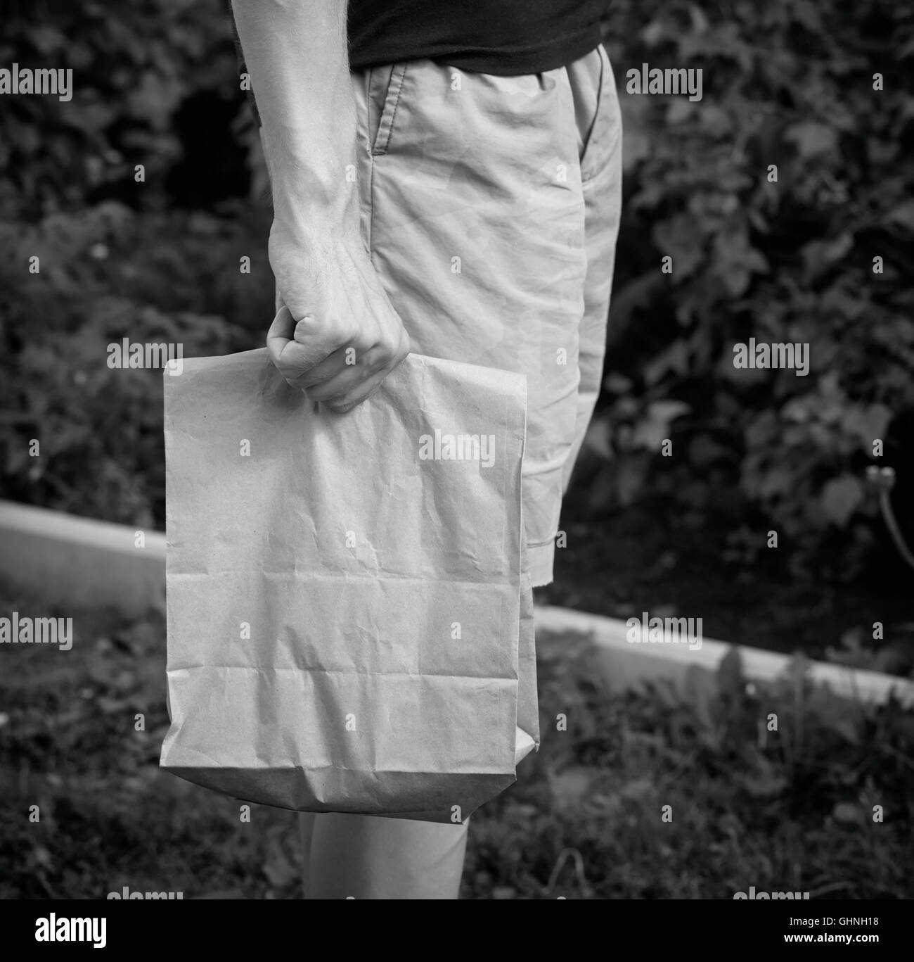 Man holding a paper bag in his hand. Black and White Stock Photo - Alamy