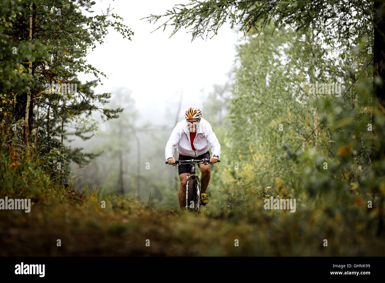 elderly male athlete mountainbiker rides in forest during Regional ...