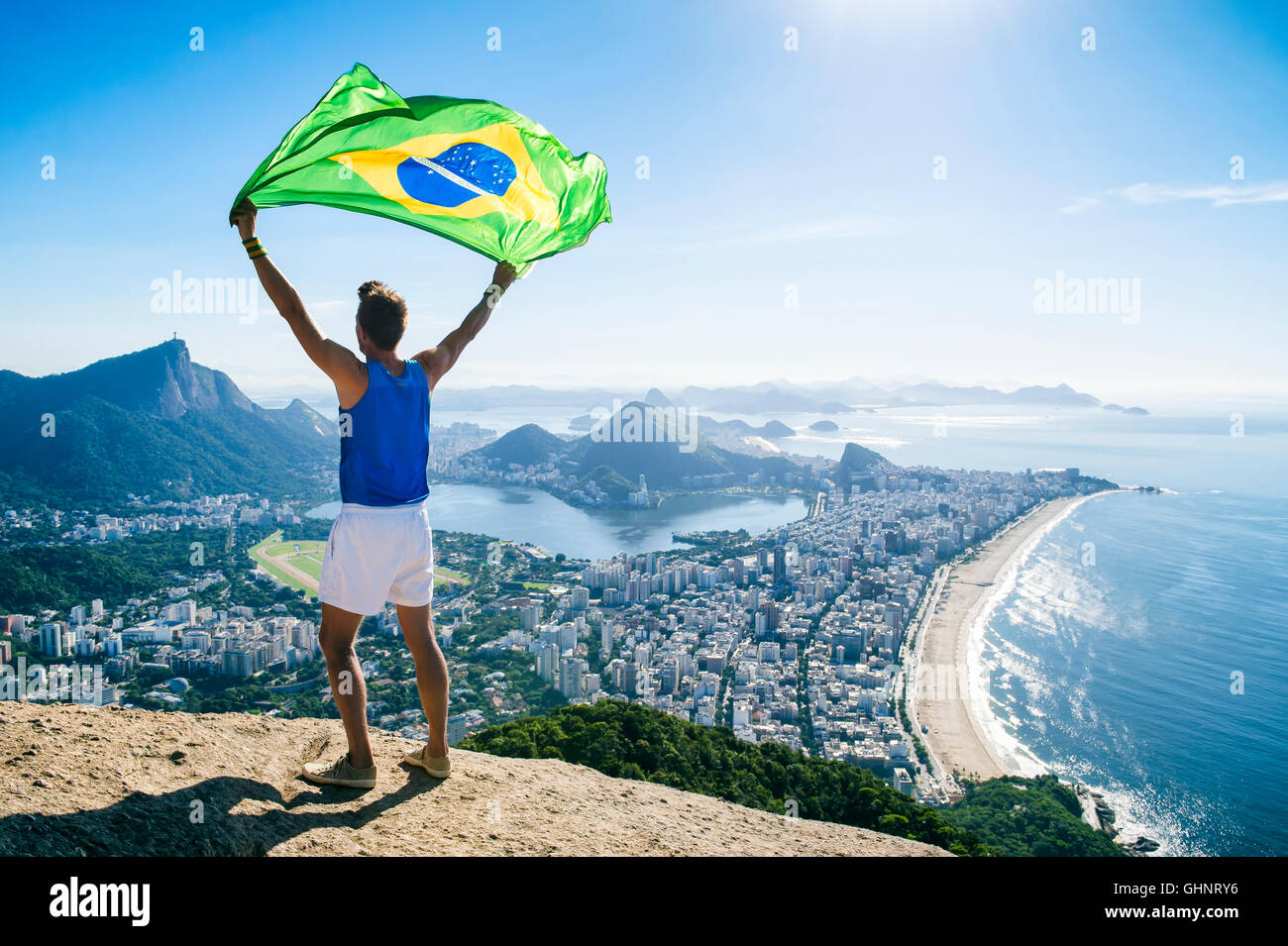 Athlete stands holding a Brazilian flag at a bright overlook of the ...