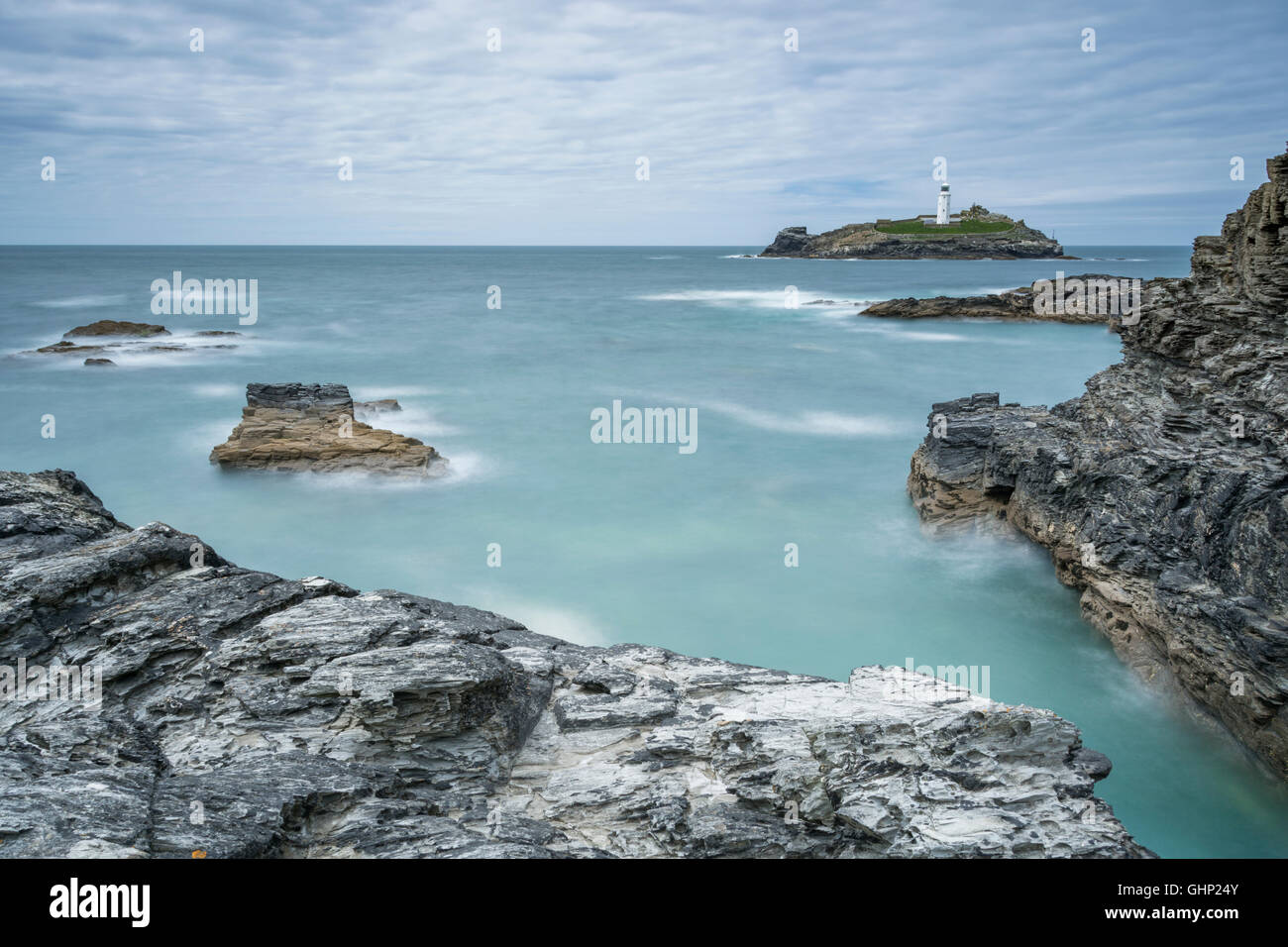 Long exposure of the rising tide on the rocks towards the lighthouse at ...