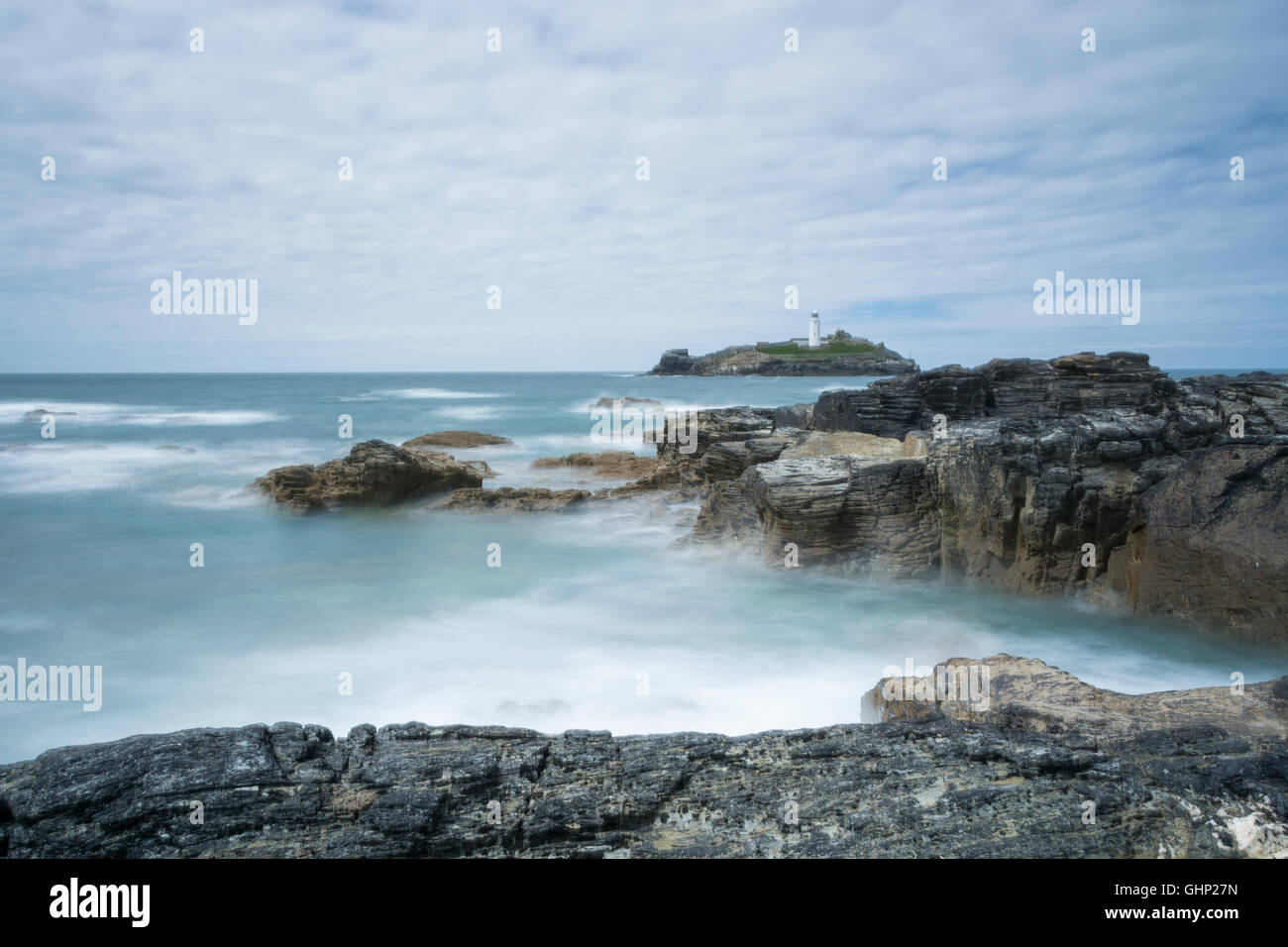 Long exposure of the rising tide on the rocks towards the lighthouse at ...