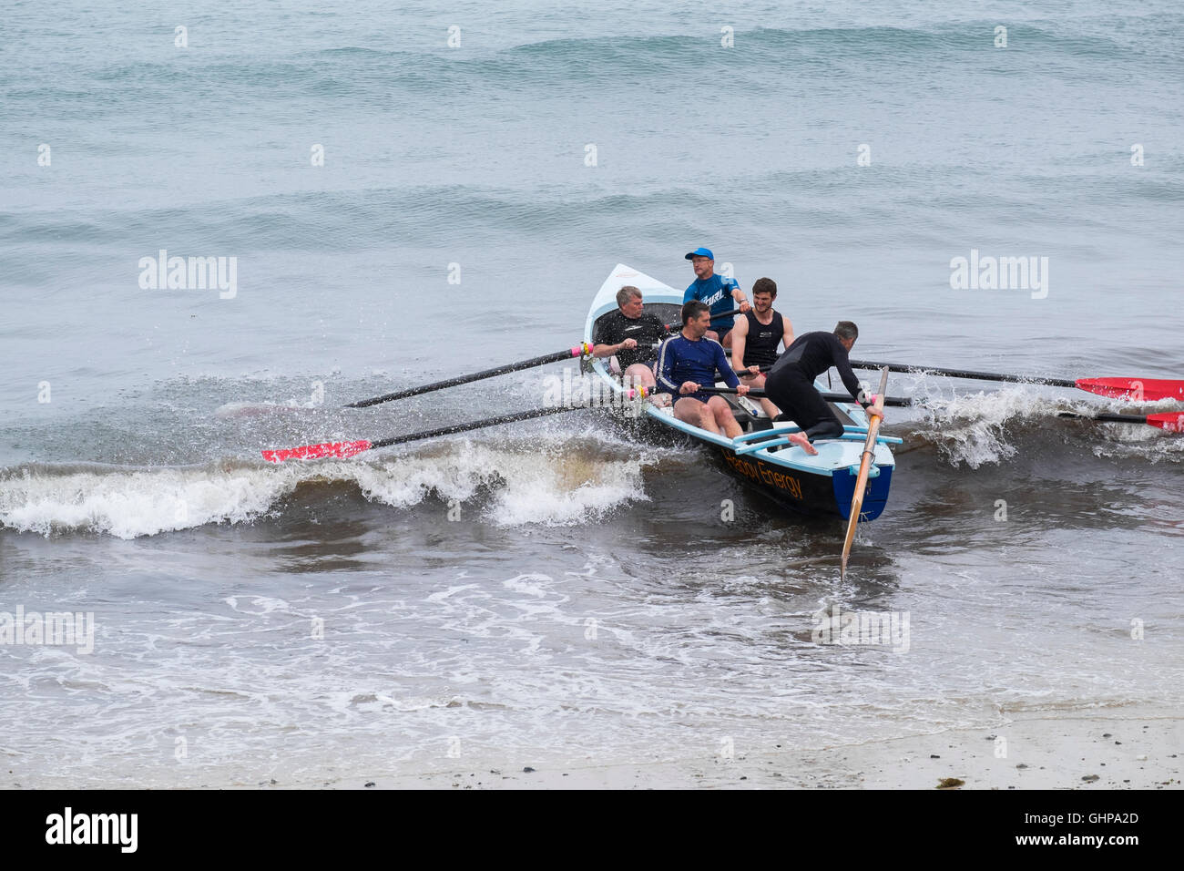 A rowing team with a gig boat on the beach at Trevaunance Cove, St ...