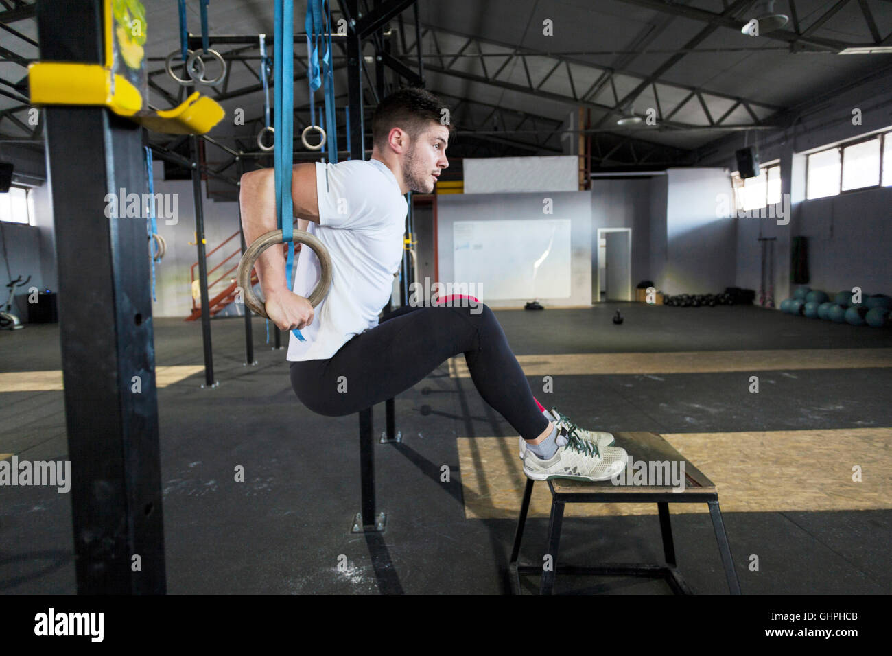 Man doing gym exercise on rings in gym Stock Photo - Alamy