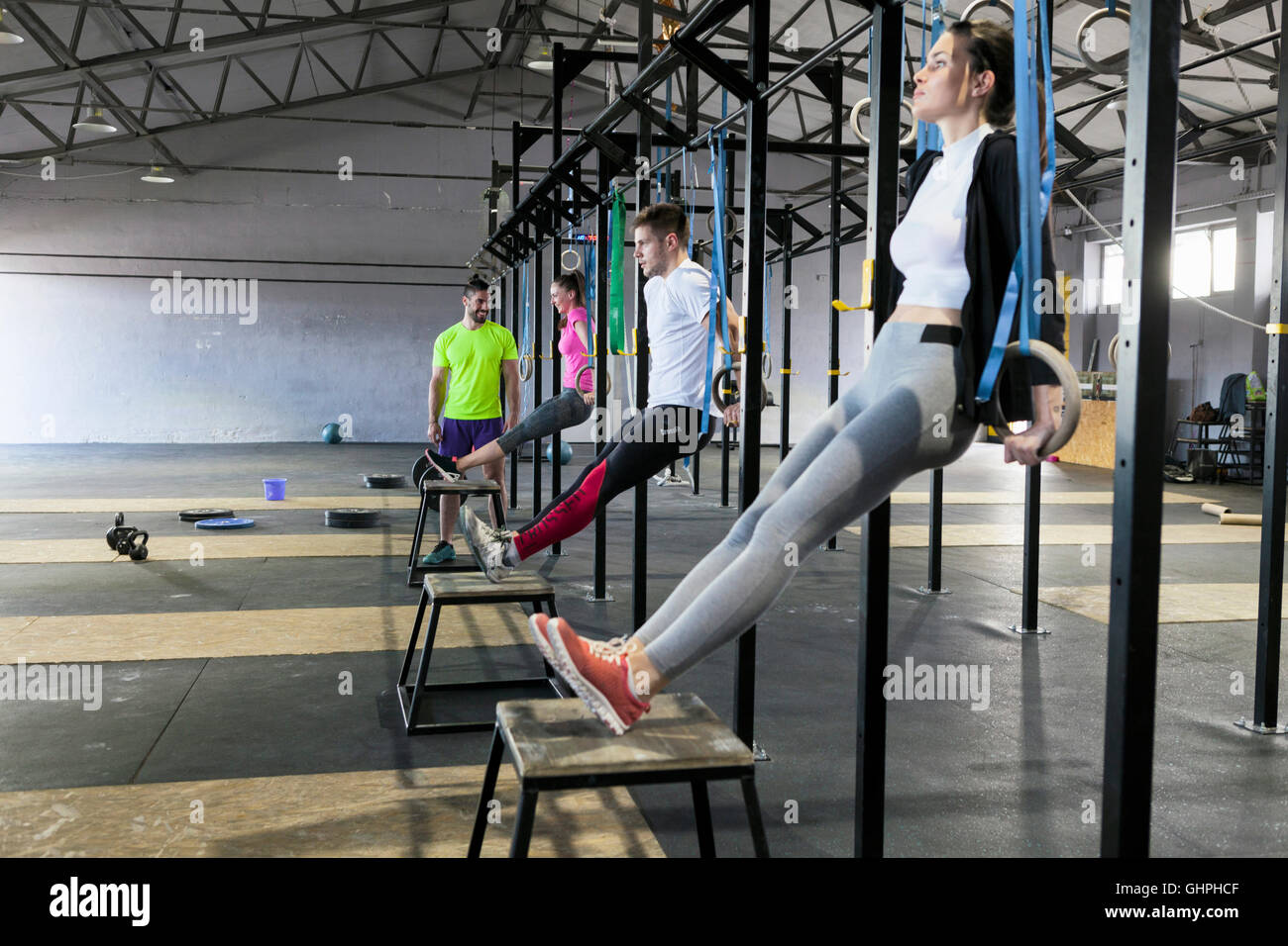 Athletes doing gym exercise on rings in gym Stock Photo - Alamy
