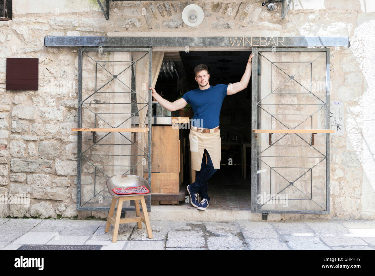 Male owner of wine bar leaning outside Stock Photo - Alamy