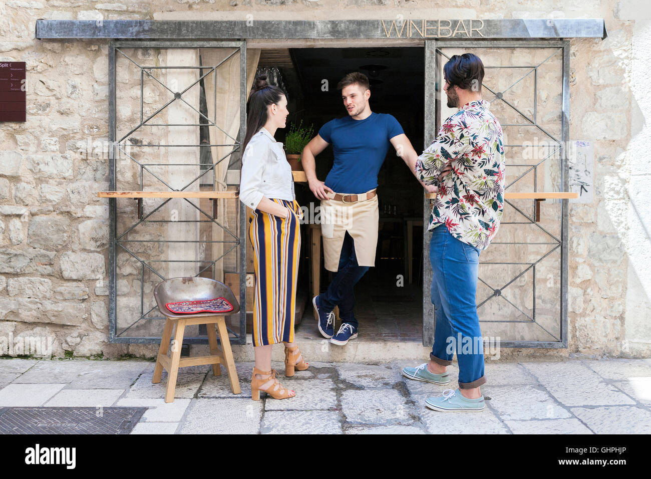 Owner of wine bar talking to friends outside Stock Photo - Alamy