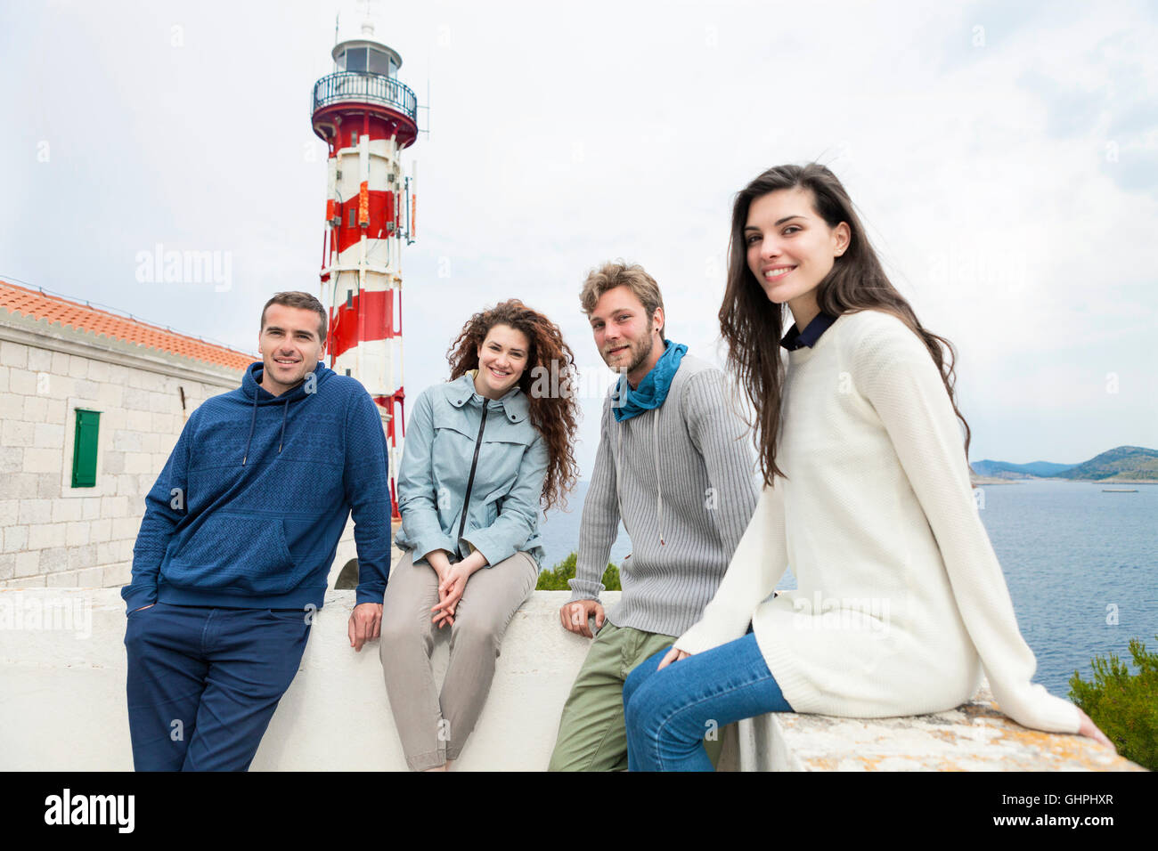 Group of friends with lighthouse in background Stock Photo - Alamy