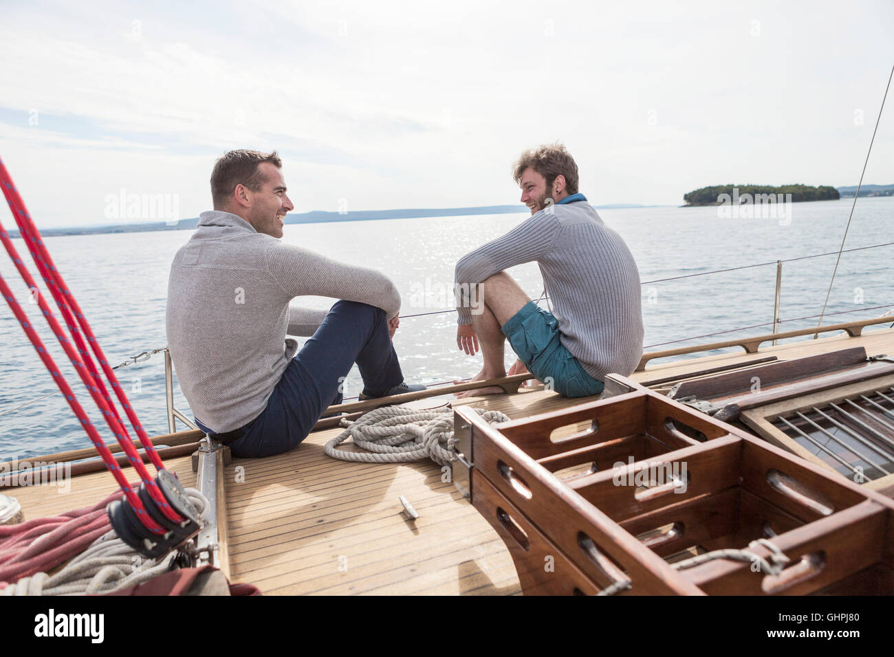 Two men sit on boat deck of yacht talking Stock Photo - Alamy