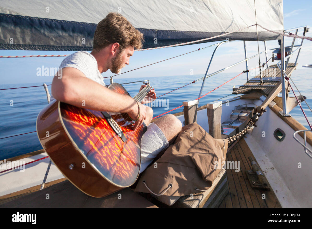 Young man playing guitar on sailboat Stock Photo - Alamy